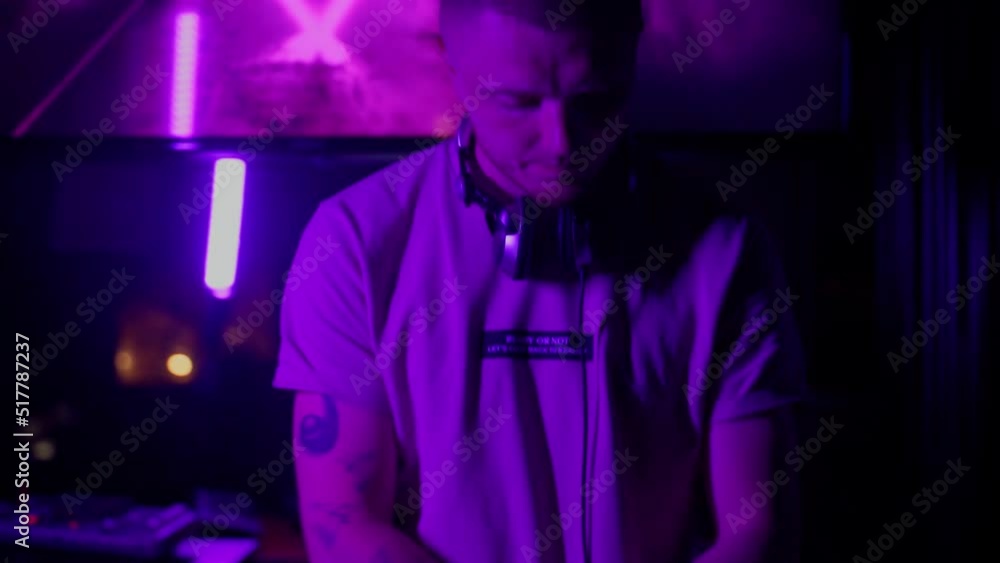 DJ in club working indoors in neon light. Caucasian male deejay person ...