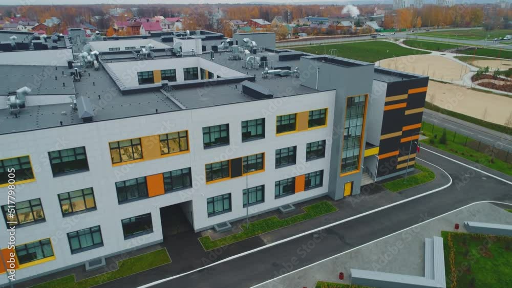 Large school building with flat roof and large windows on city street ...
