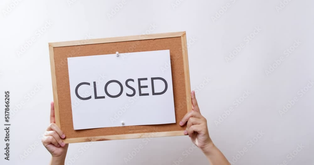 Woman's hand shows the paper on board with the word CLOSED in white ...