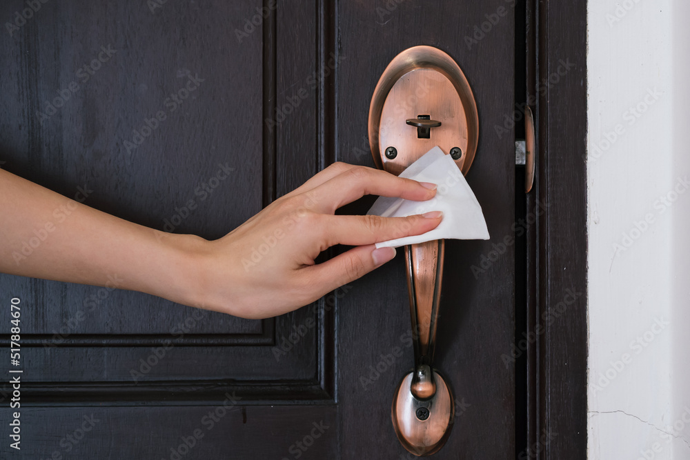 Ladies hand wiping the wooden front door bronze colour handleset by ...
