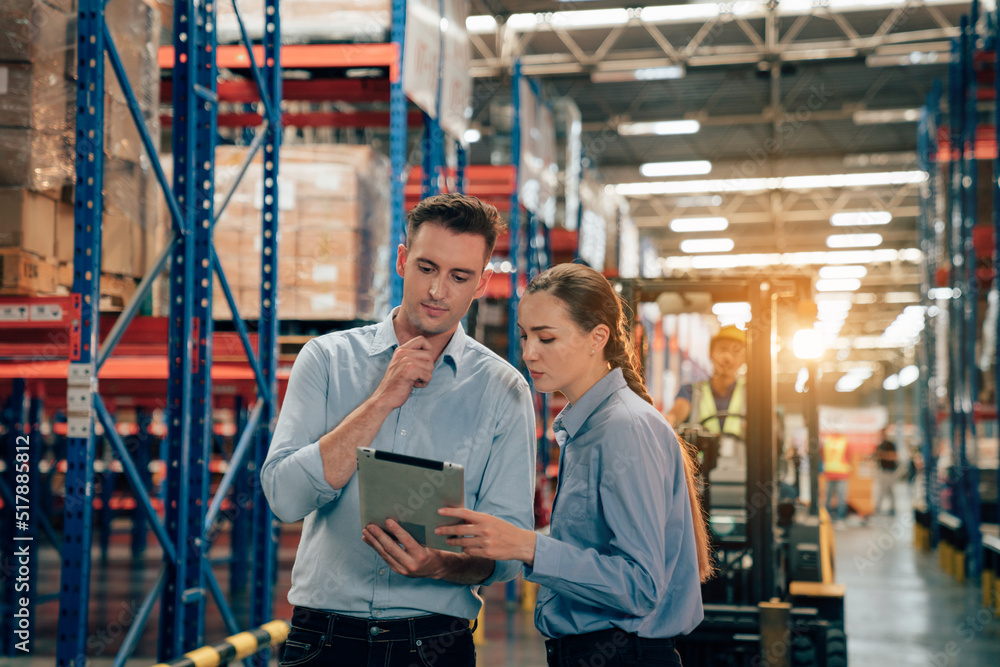 Warehouse manager talking and using digital tablet while checking ...