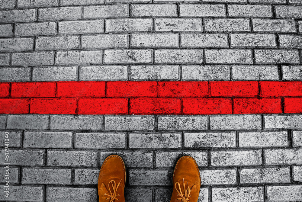 Red line on the brick road and feet in brown shoes. Someone is standing ...