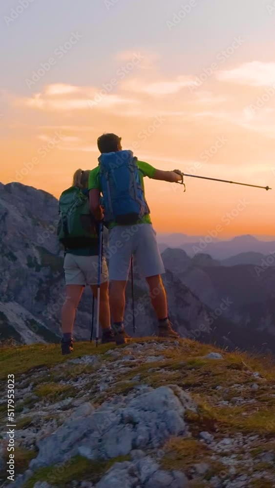 DRONE: Young hiker couple watch the sunrise from a grassy mountaintop ...