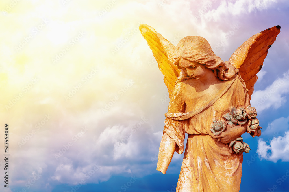 Beautiful guardian angel in sun rays. Fragment of a very ancient stone ...