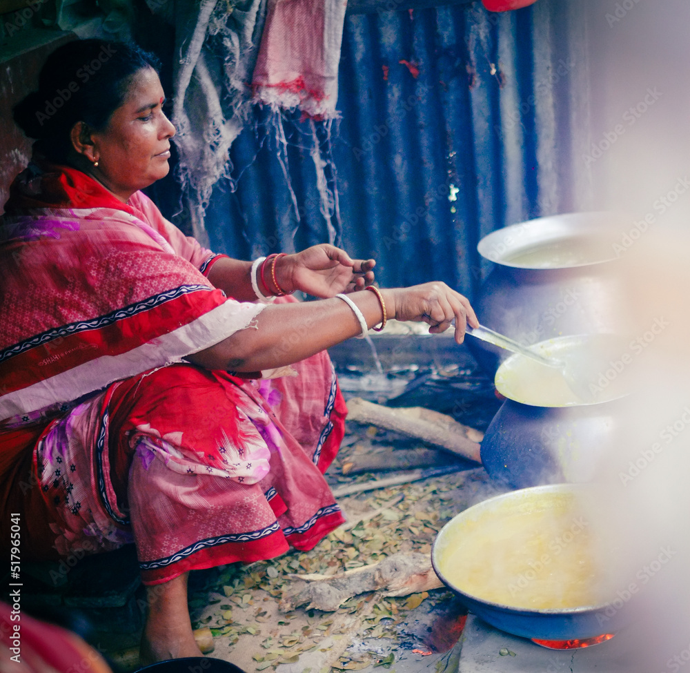 South asian woman wearing traditional clothes cooking in village house ...