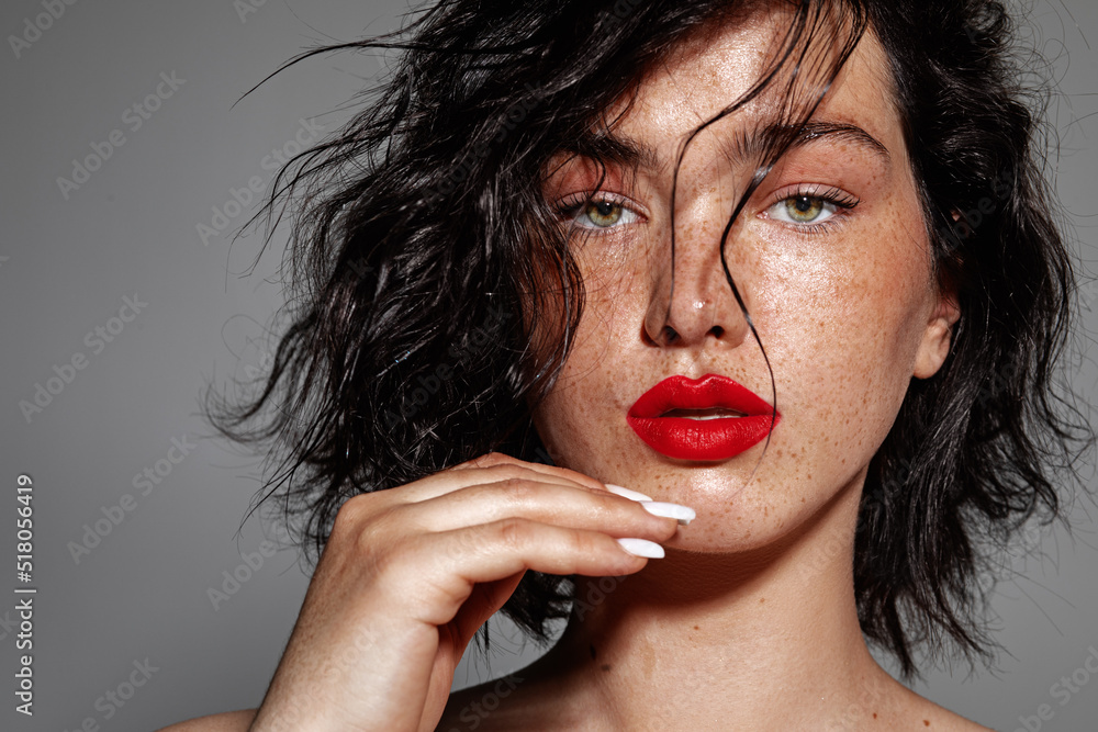 beauty young woman face with a lot of freckles and red lips, hand near ...