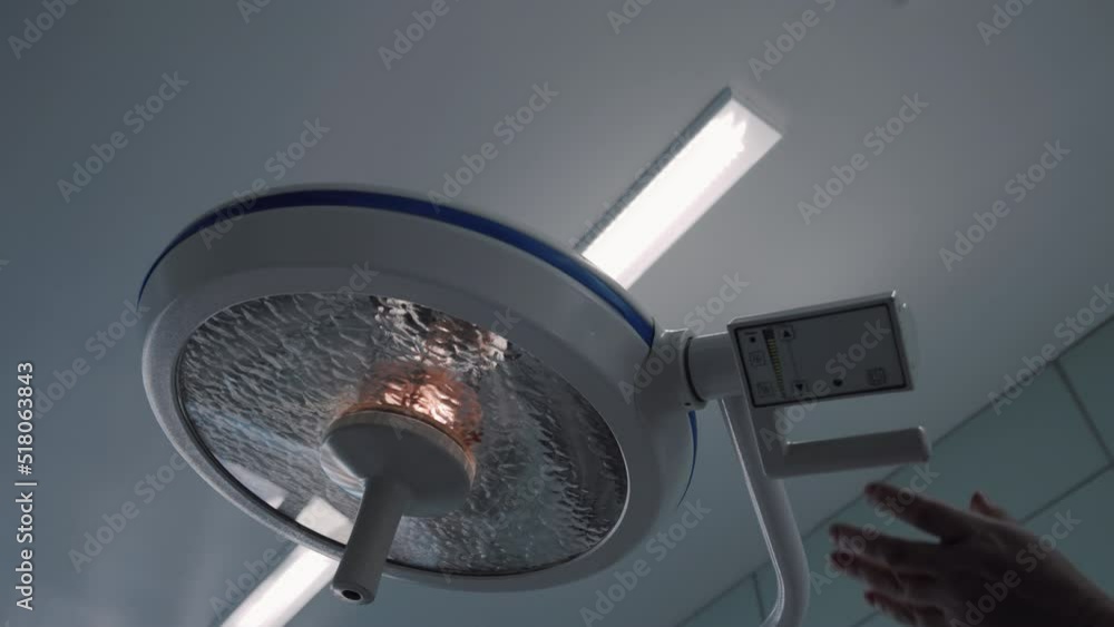 Scrub nurse hand turning on shadowless surgical LED light pressing ...