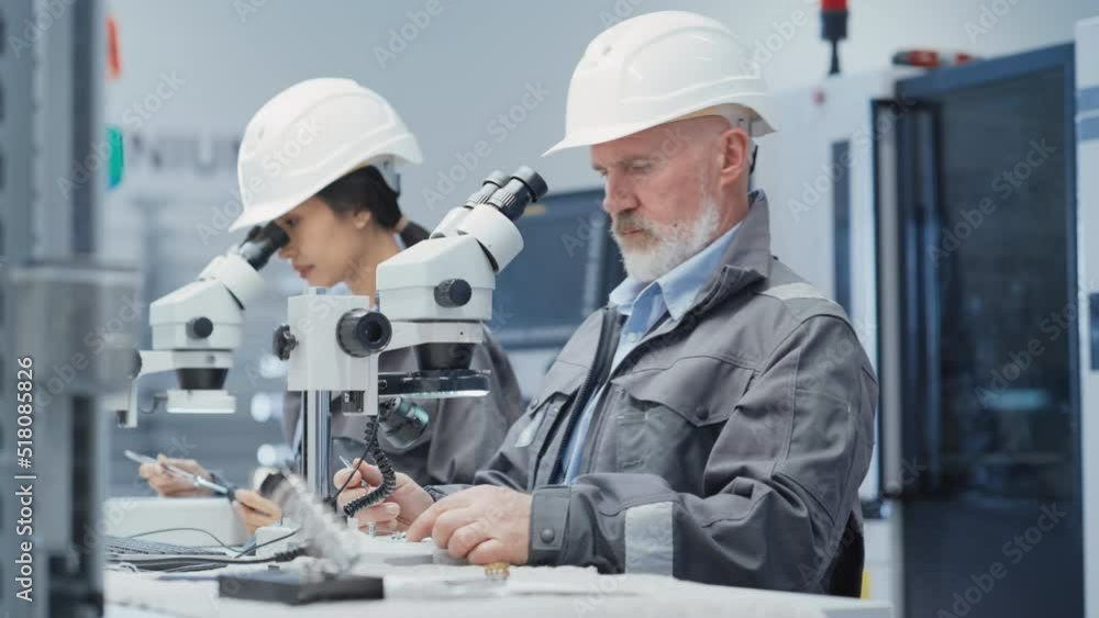 Middle Aged Industrial Scientist and Younger Asian Engineer Working at ...