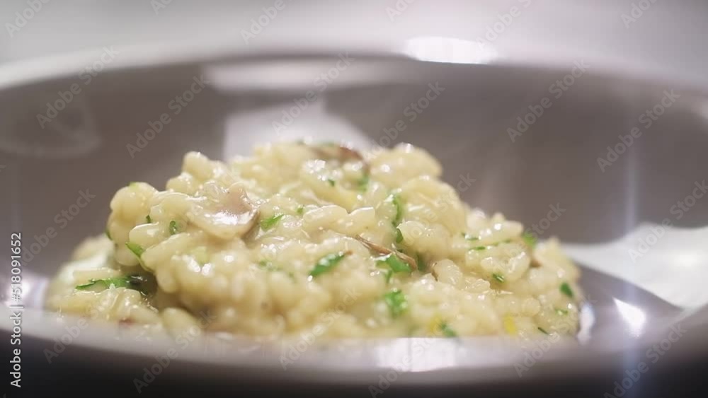 Serving of risotto with mushroom in a plate, slow motion. vídeo de ...