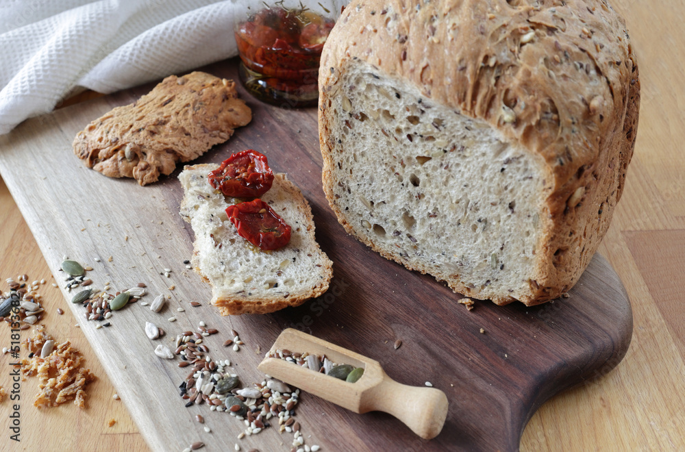 loaf of homemade whole grain bread and a cut off slice of bread. A ...