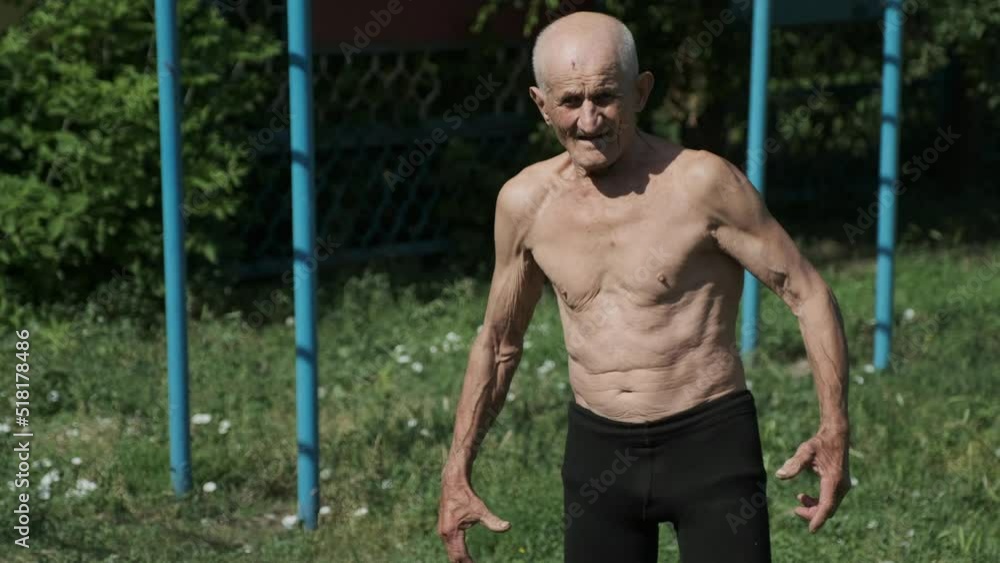 Strong very old man with bare torso demonstrates arms muscles on ...