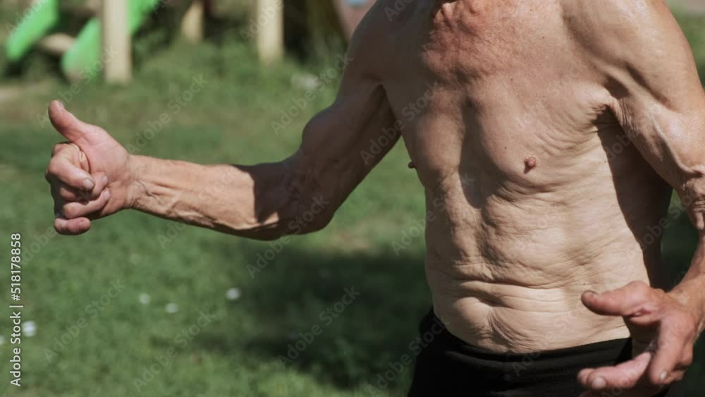 Old wrinkled man shows strong body drawing in abdominal muscles closeup ...