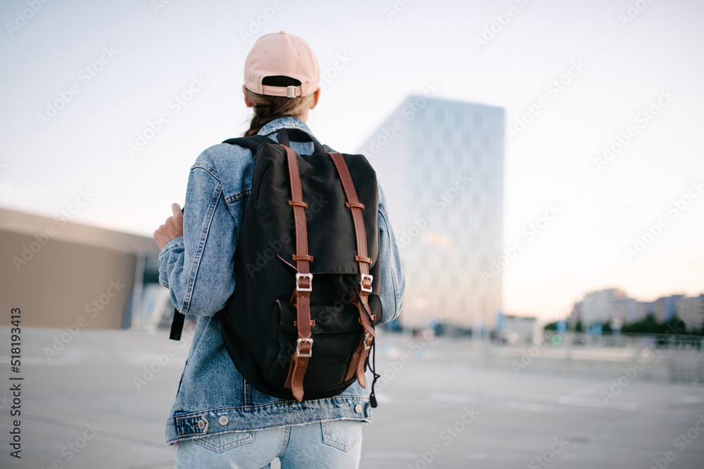 Tourist girl with her backpack looking at city landscape, back view ...