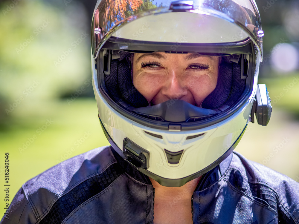Young female motor cyclist wearing a full face helmet with visor open ...
