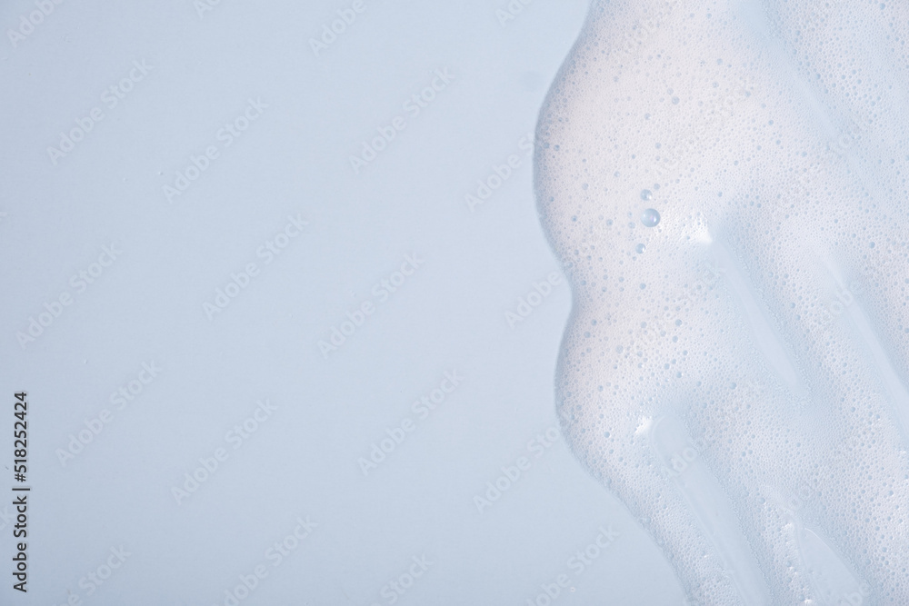 Face cleansing mousse sample. White cleanser foam bubbles on blue ...