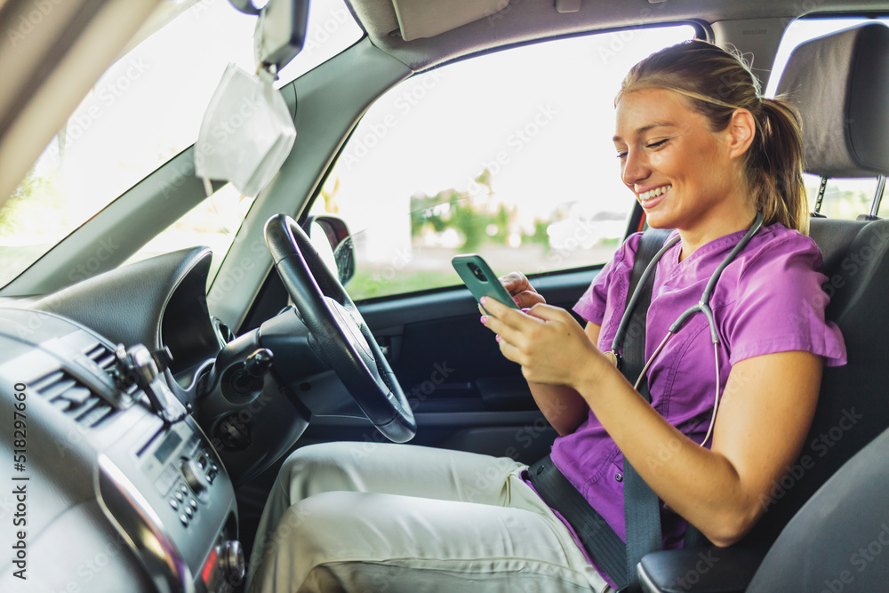 Nurse arriving at a patient's home, she is sitting in her car using her ...