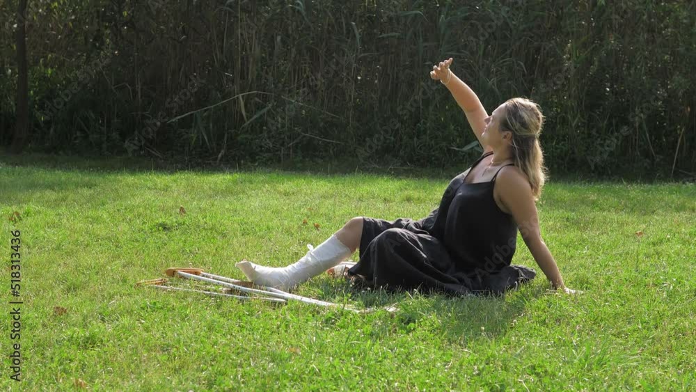 A young girl with a cast and a walker is sitting on the lawn in the ...