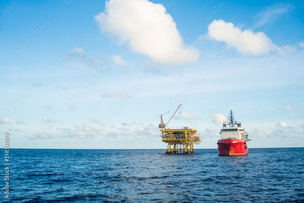 A tugboat anchors near an oil rig at an oil well to transport necessary ...