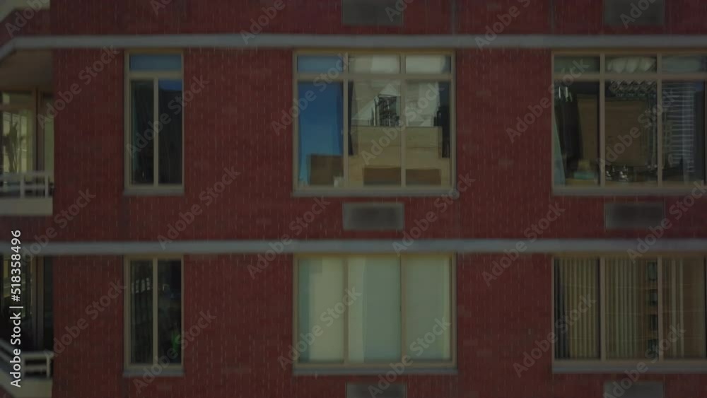 Ascending fly along red brick wall with windows. Revealing view of ...