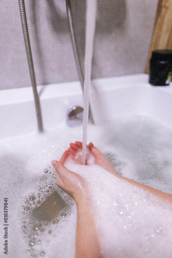 Person holding hands under water with lather, which pouring from tap ...