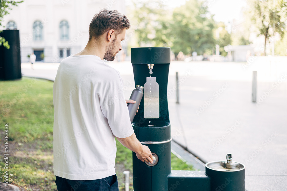 Man refilling his water bottle at the city. Free public water bottle ...
