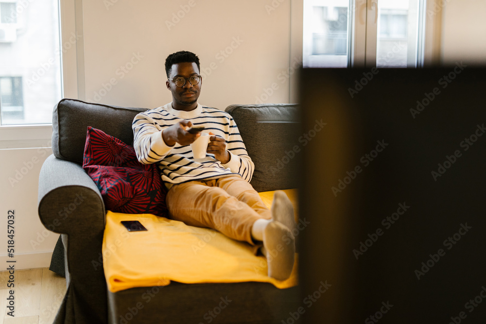 Man sitting and changing tv channels at home Stock Photo | Adobe Stock