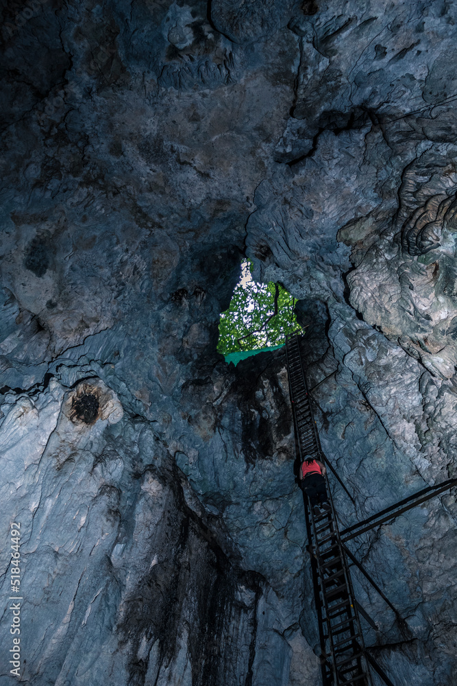 adventurous woman descending inside a deep cavern by metal stairs ...