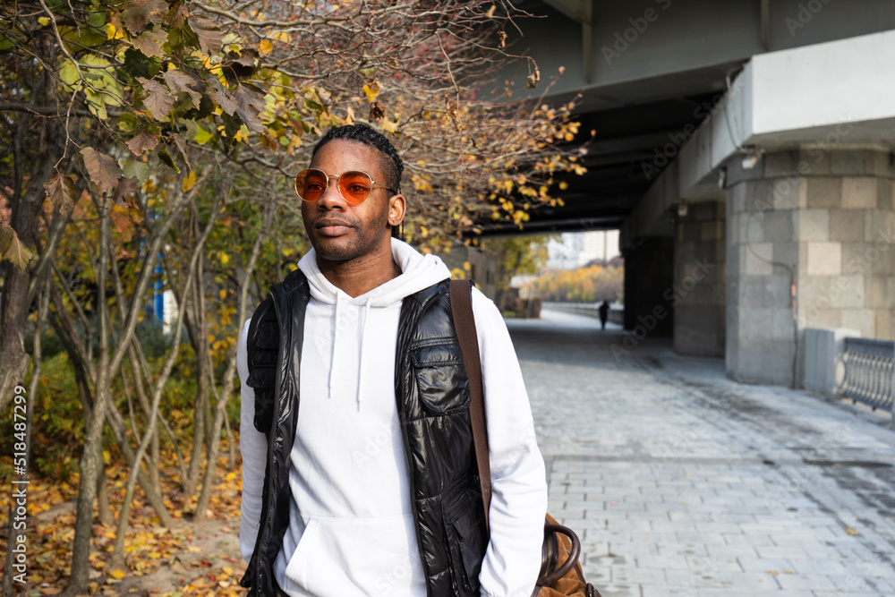 Stylish handsome black man walking by a tunnel and trees Stock Photo ...