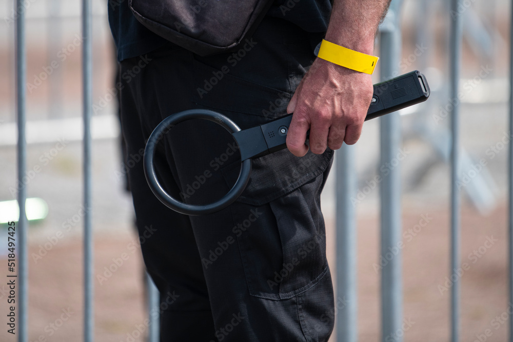 Security check metal detector device in hand of staff worker on check ...