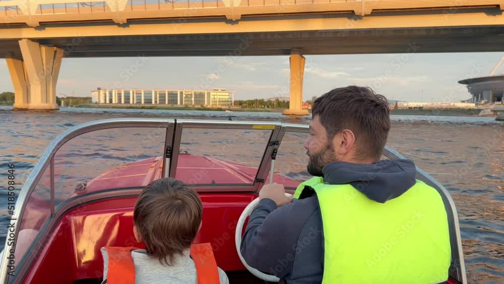 Father and son riding motor boat wearing safety vests having a ride in ...