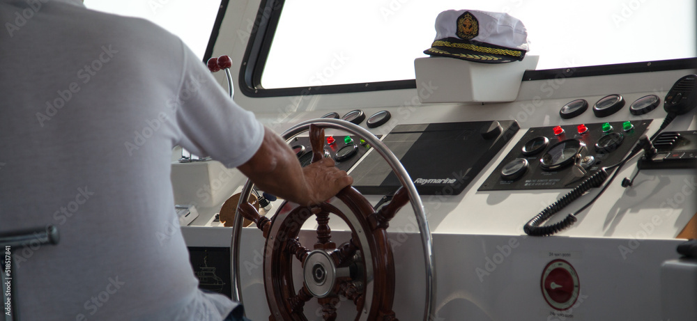 The captain of the ship holds the helm with his hand and the captain's ...