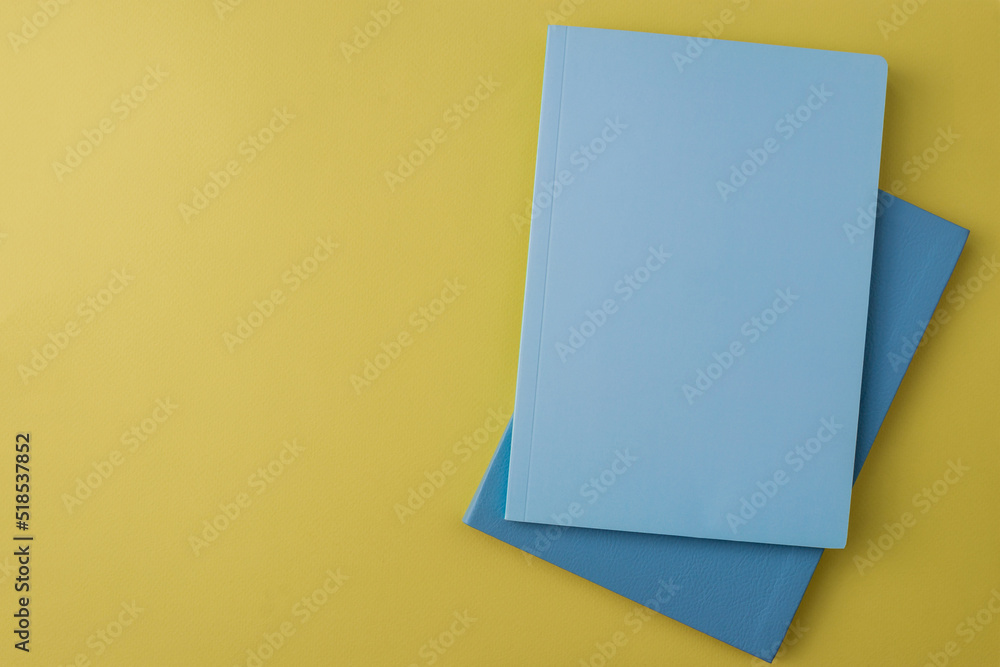School notebooks of blue color are located on a yellow background ...