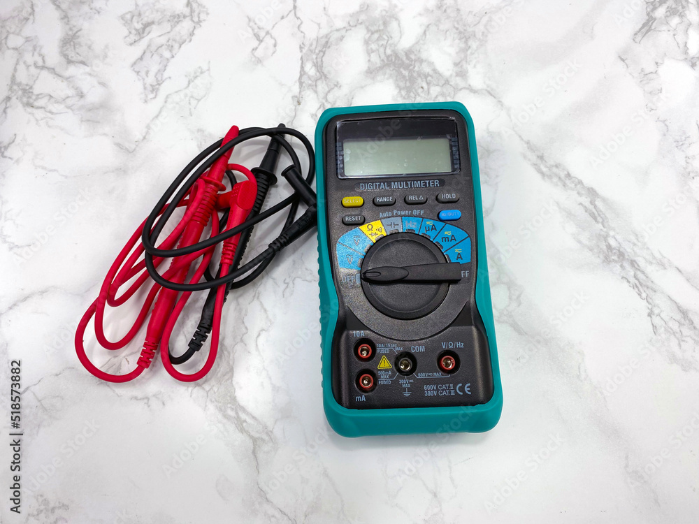 Digital multimeter with probes and backlit display on a white marble ...