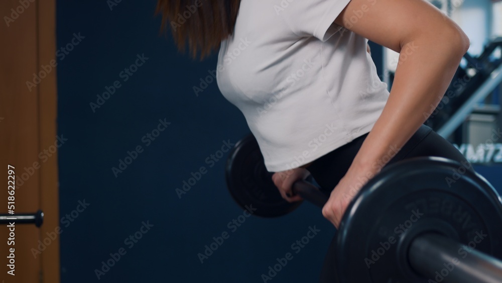 Athletic woman pumps muscles using a barbell with a weight. Classes in ...