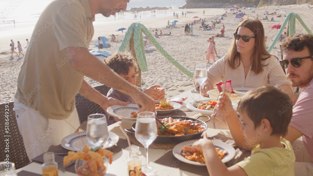 Family and friends gathered for lunch enjoying a delicious paella in a ...