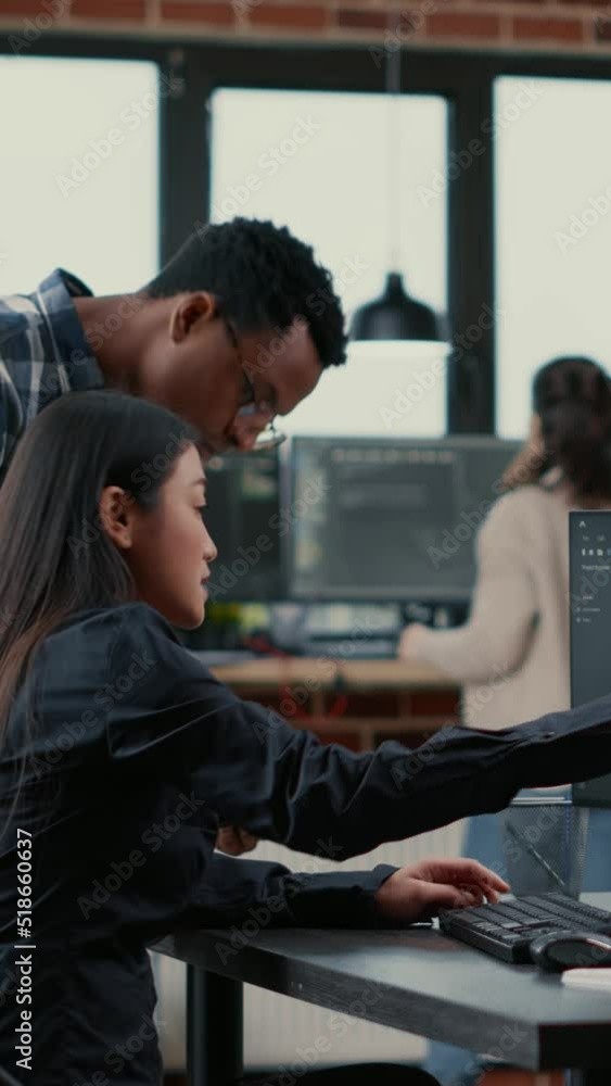 Vertical video Mixed team of software developers analyzing source code pointing at screens ...