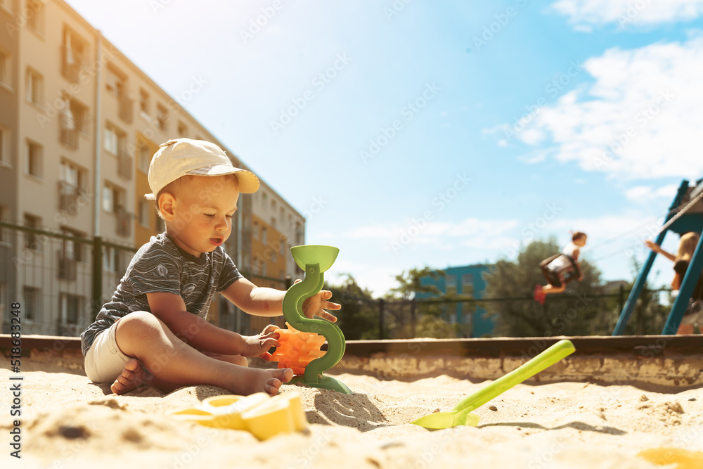 Child playing in sandbox. Little boy having fun on playground in sandpit. Outdoor creative ...