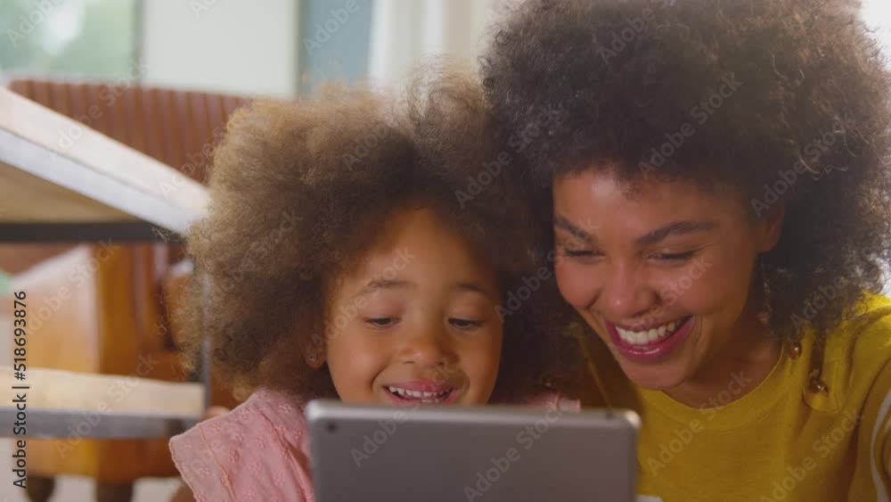 Mother and daughter having fun lying on floor streaming movie on ...