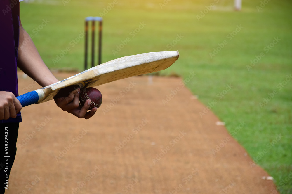 Cricketer holds old red leather cricket ball and cricket bat in hands ...