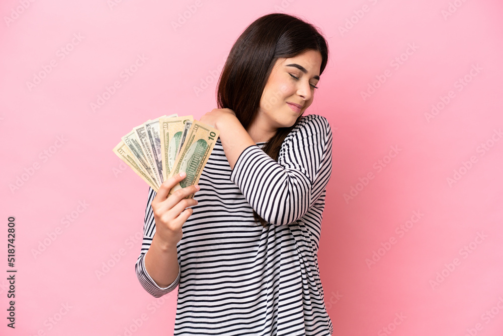 Young Brazilian woman taking a lot of money isolated on pink background ...
