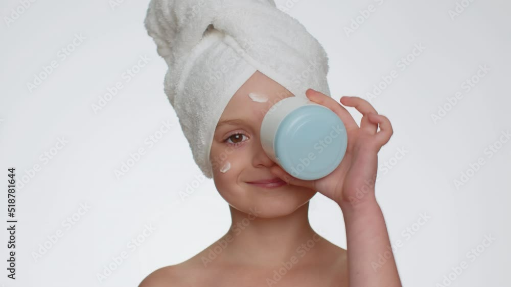 Beautiful young smiling child girl applying cleansing moisturizing ...