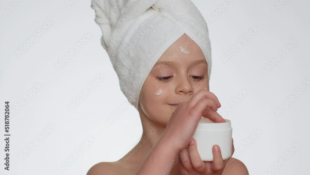 Lovely young child girl with towel on head applying cleansing ...