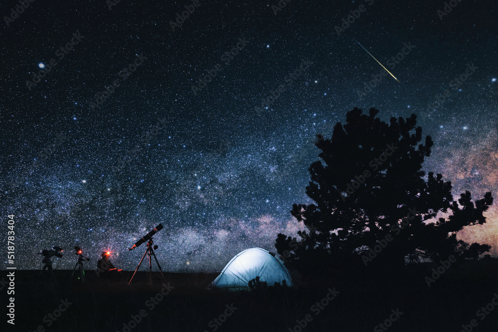 Amateur astronomer with astronomical telescope camping in nature under ...