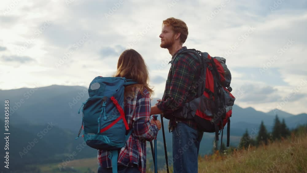Two backpackers look sunrise mountains landscape. Hiking couple relax ...
