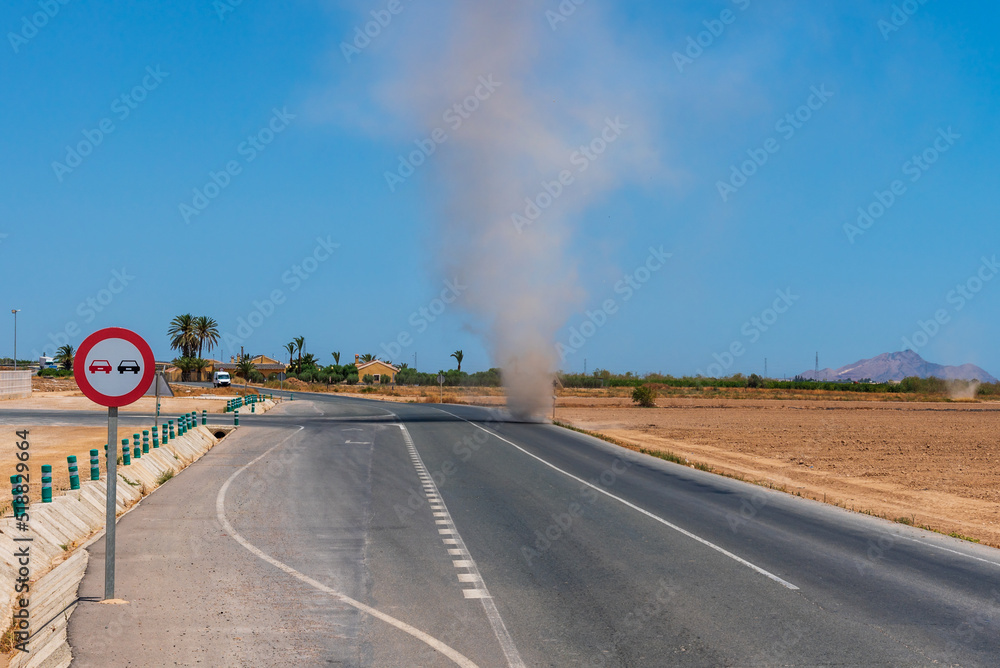 Dust devil created by high ground temperatures crossing a highway ...
