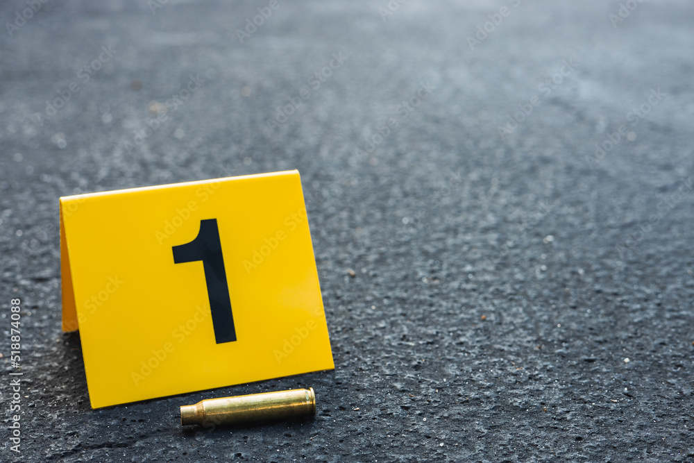 One yellow crime scene evidence marker on the street after a gun ...