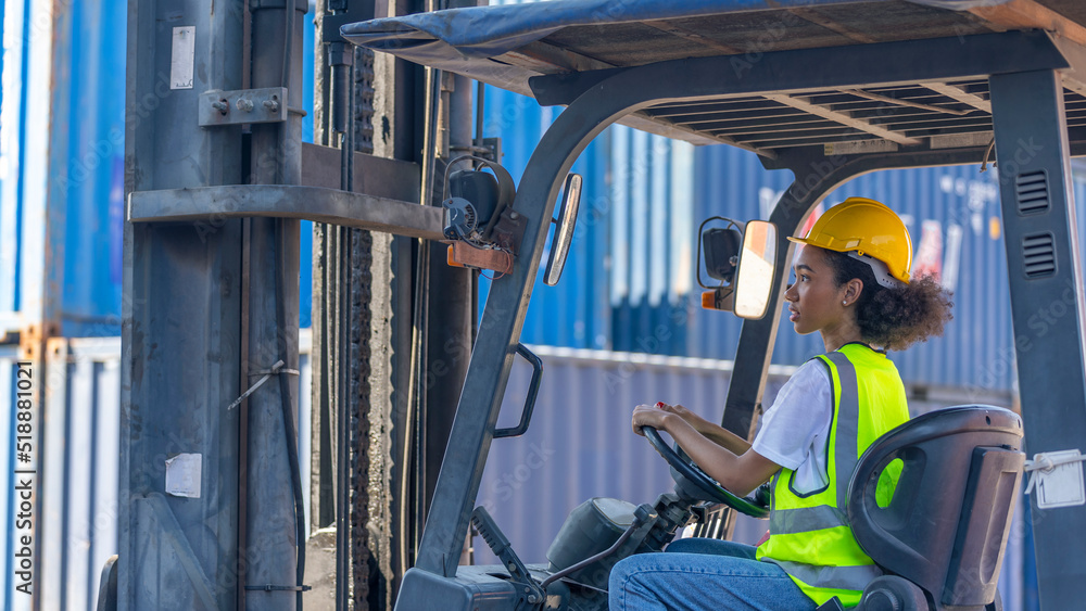 Young African American lady operates a forklift tractor to move ...