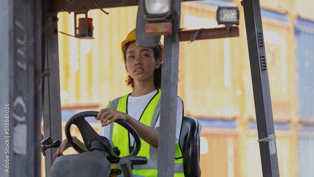 Fotka „Young African American lady operates a forklift tractor to move ...
