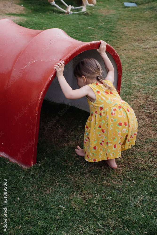 Little toddler girl playing on the kids playground. Hide and seek game ...