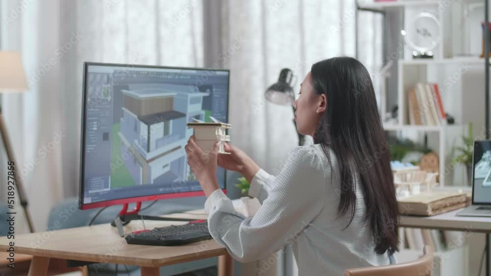 Asian Woman Engineer Holding And Looking At The Small House Model With ...